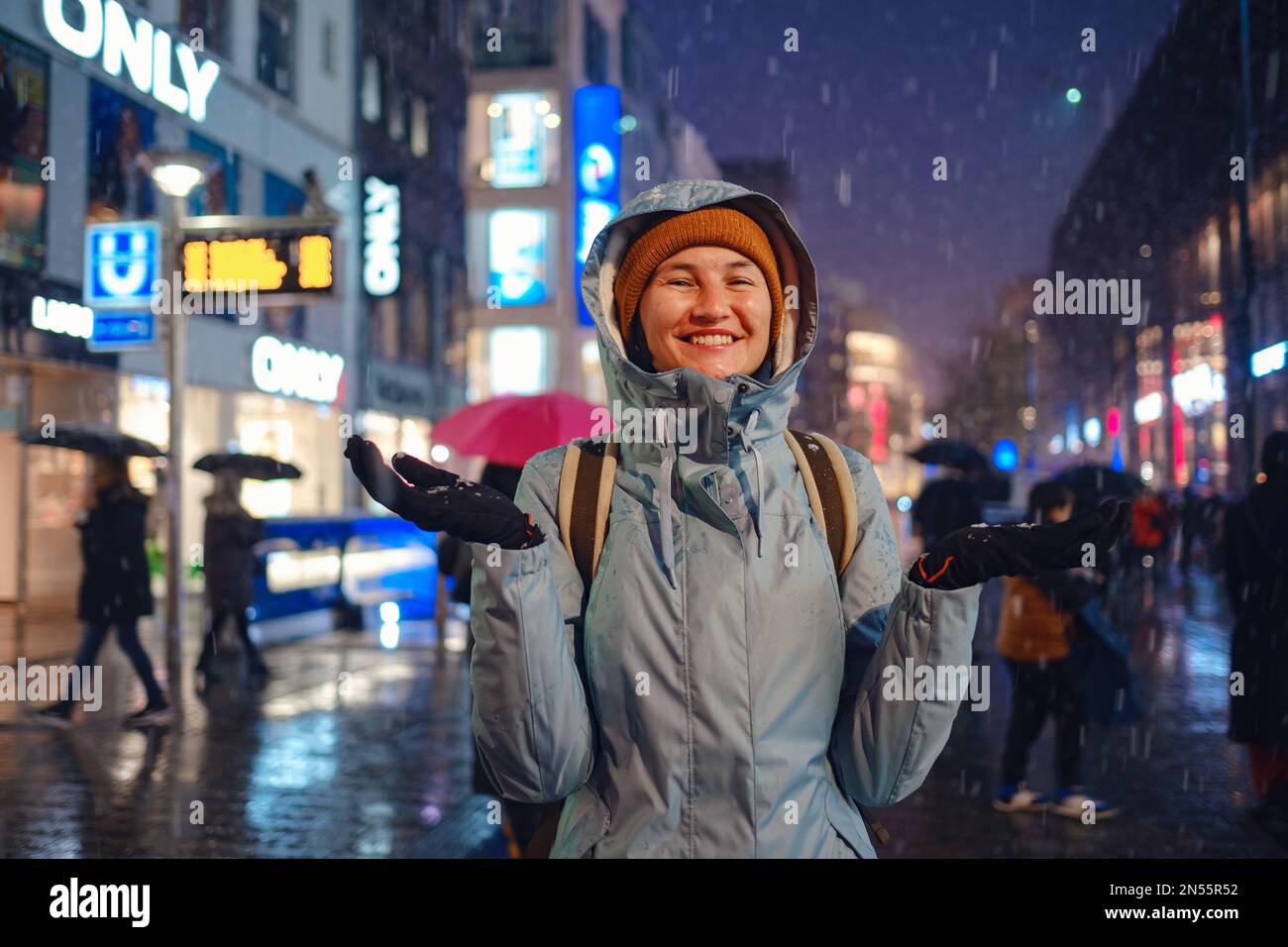 snowfall woman in a blue jacket and yellow hat christmas outside, city ...
