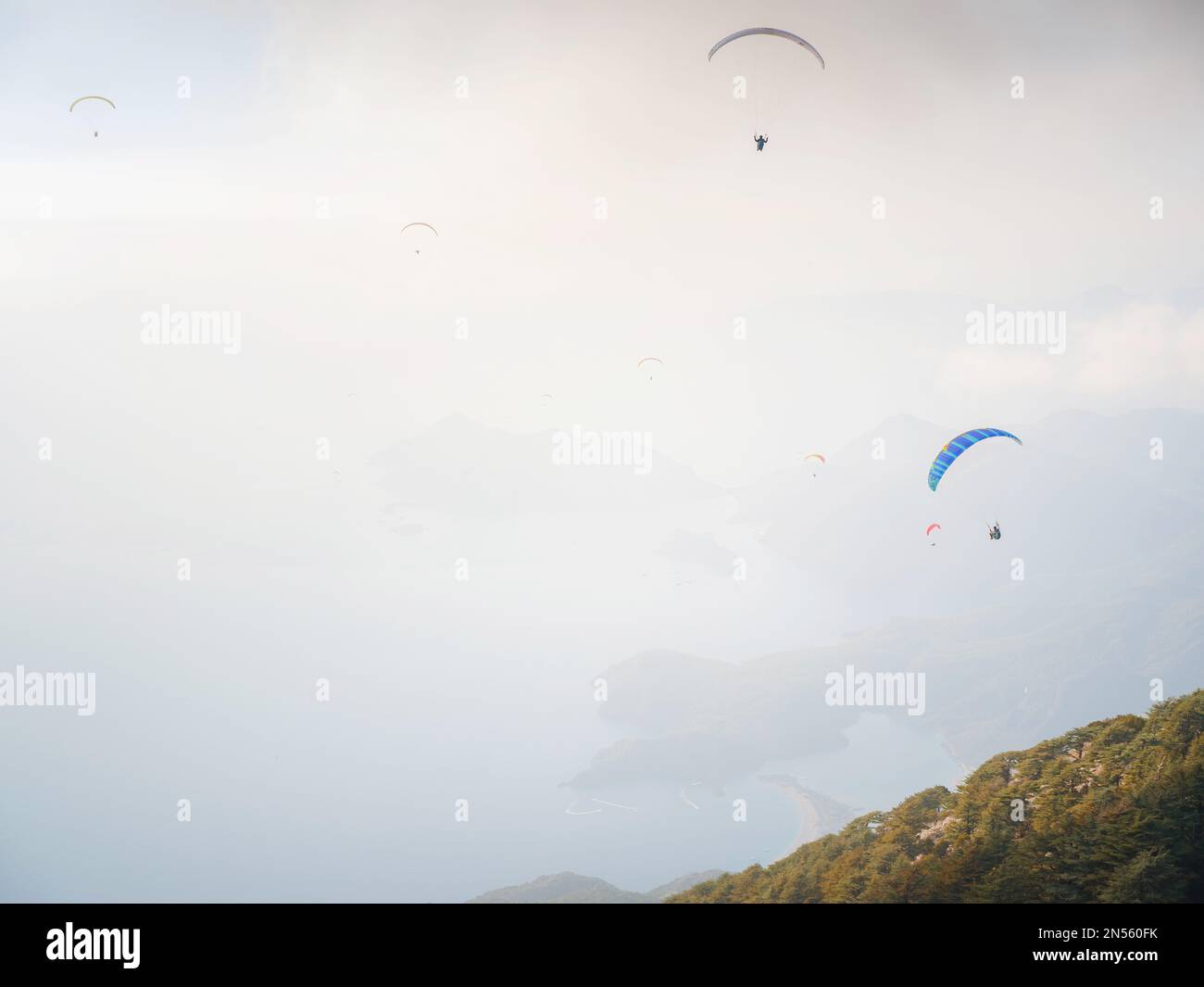 Paragliding in sky. Paraglider tandem flying over sea and mountains in ...