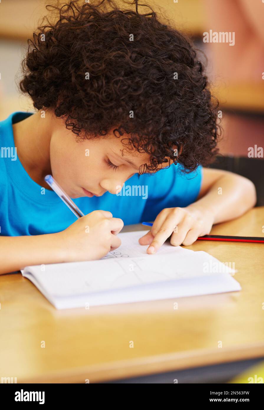 Writing in his homework book. A cute little boy working on his homework ...