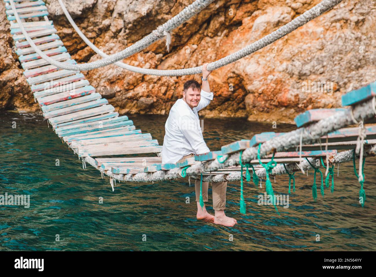man sitting at suspension bridge enjoying sea view and nature calmness ...