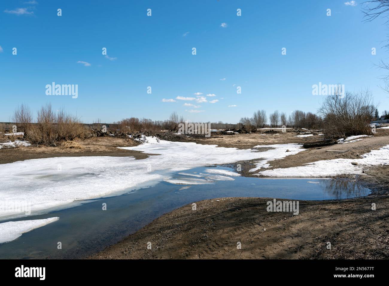 Spring Bay of the river with clear water and ice and snow on the sandy ...