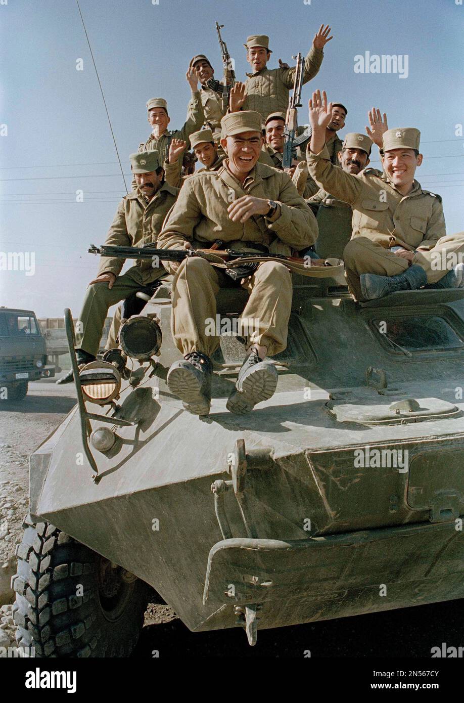 A group of Afghan army soldiers manning a withdrawal checkpoint wave to ...