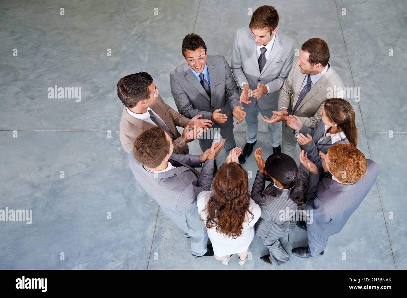 Hes an inspiration. A business team standing in a circle and applauding ...