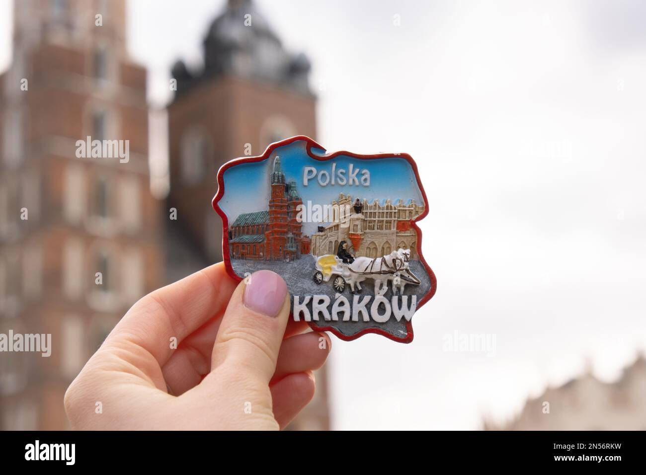 Female hand holding souvenir magnet next to St. Mary's Basilica on the ...