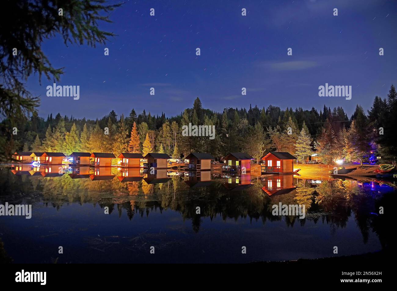 Small, illuminated cabins by a lake, starry sky, petitt train the north ...