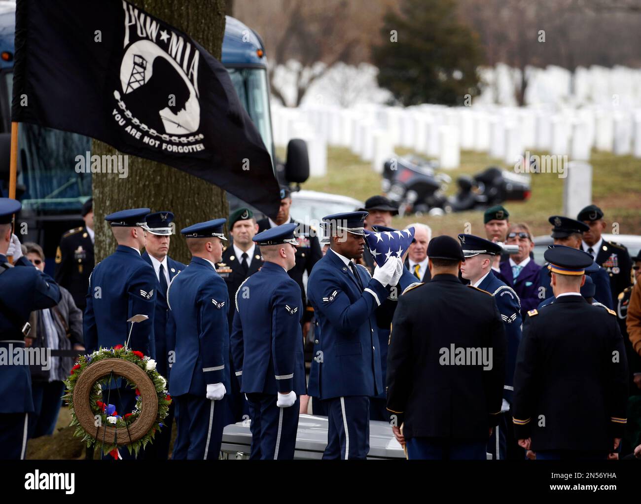 A folded American flag is held up as the POW-MIA flag flies during a ...