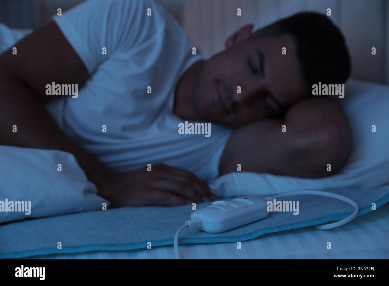 Man sleeping in bed with electric heating pad, focus on cable Stock ...