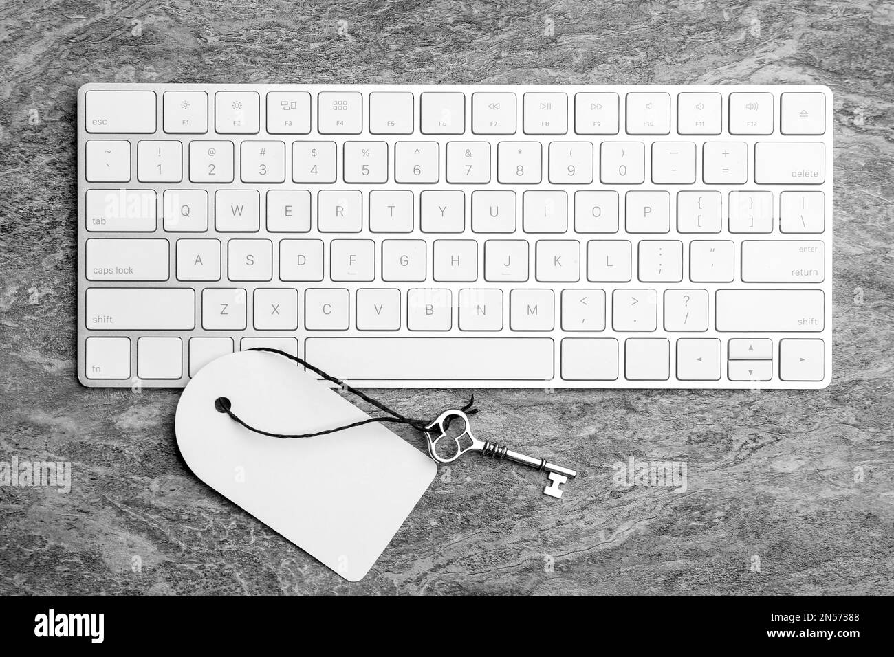 Key with blank tag and computer keyboard on grey table, flat lay ...