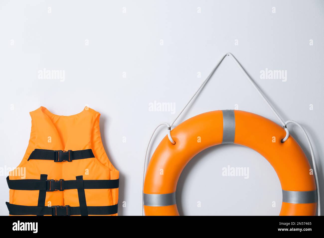 Orange life jacket and lifebuoy on light background. Rescue equipment ...