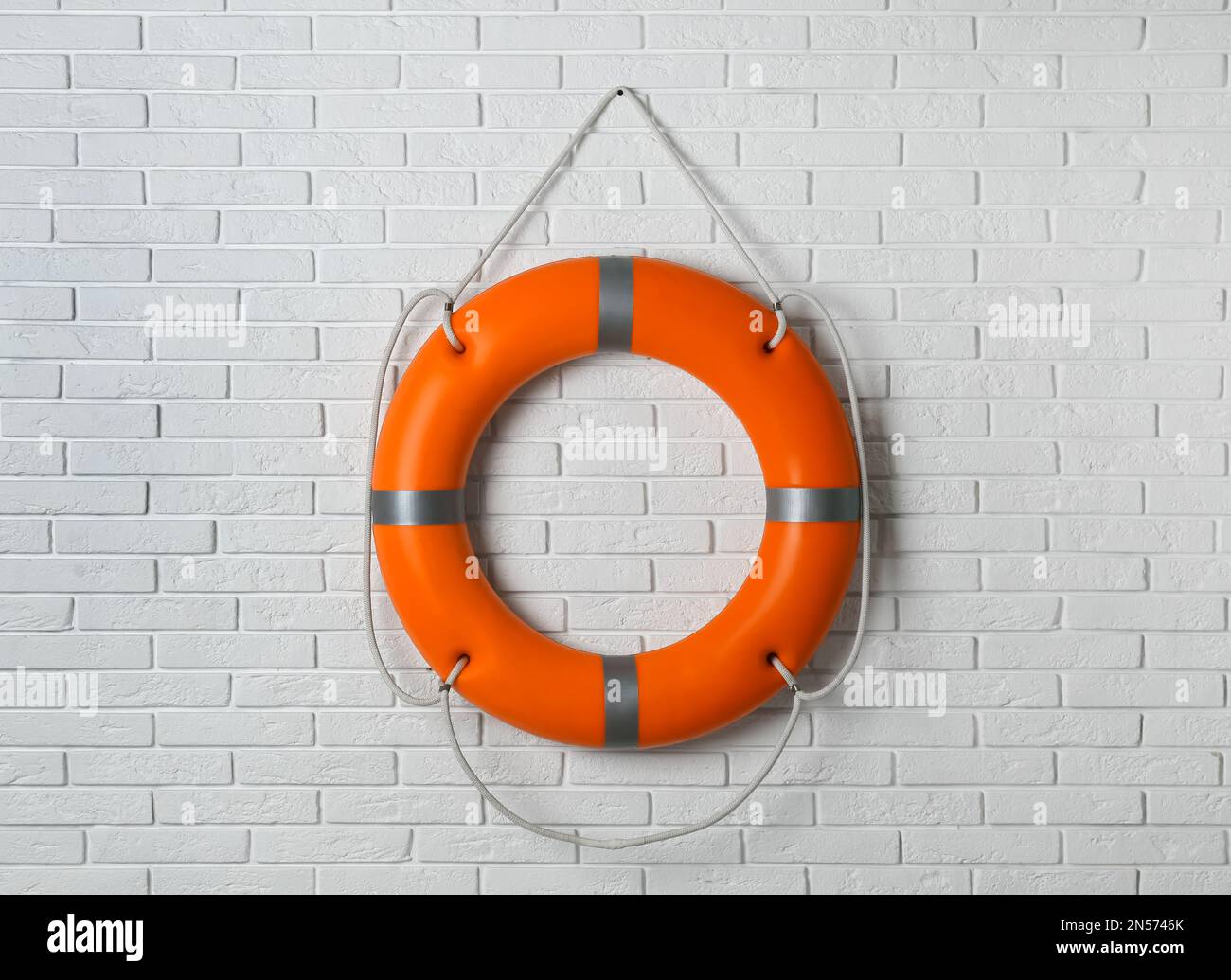 Orange lifebuoy on white brick wall. Rescue equipment Stock Photo - Alamy