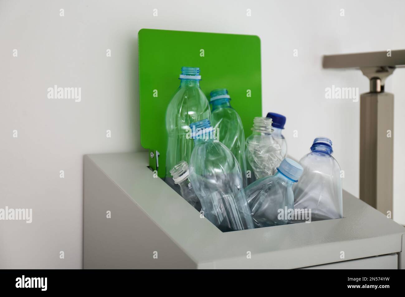 Many used plastic bottles in metal bin indoors, closeup. Recycling ...