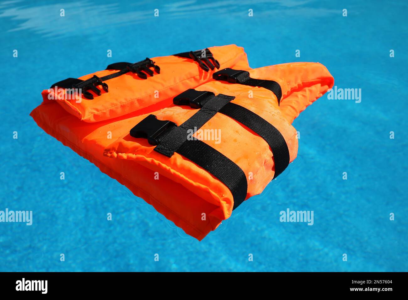 Bright orange life jacket floating in swimming pool Stock Photo - Alamy