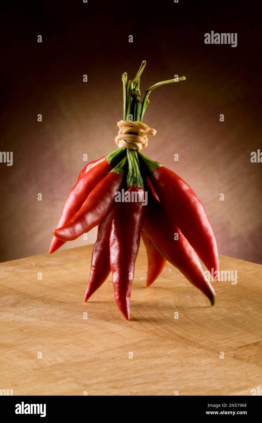 Bunch of red chilli peppers sitting on a timber bench Stock Photo - Alamy