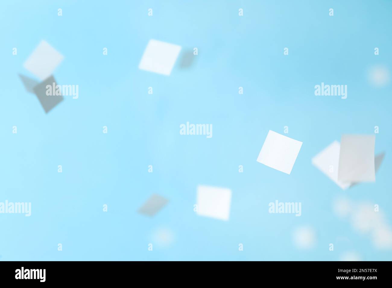 White confetti falling down on light blue background Stock Photo - Alamy