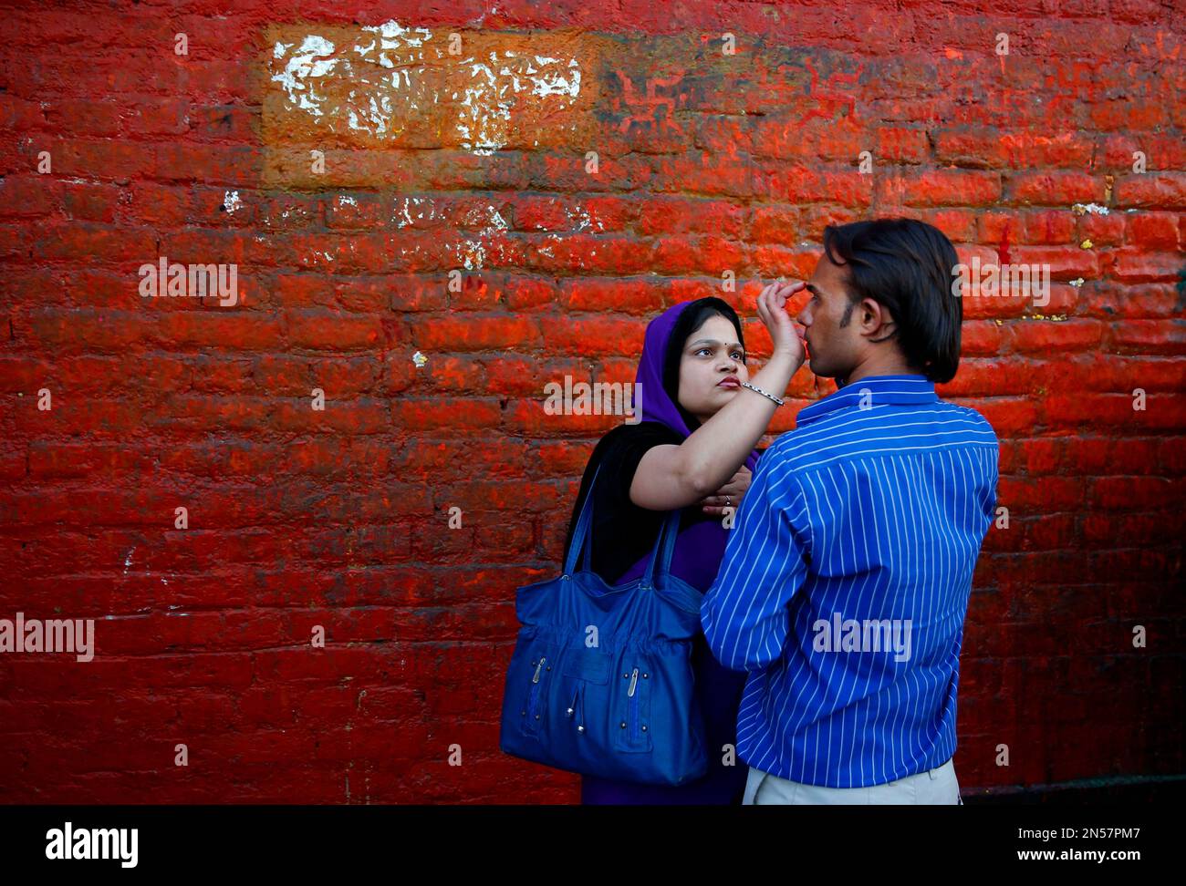A woman applies vermillion mark on the forehead of her husband after ...