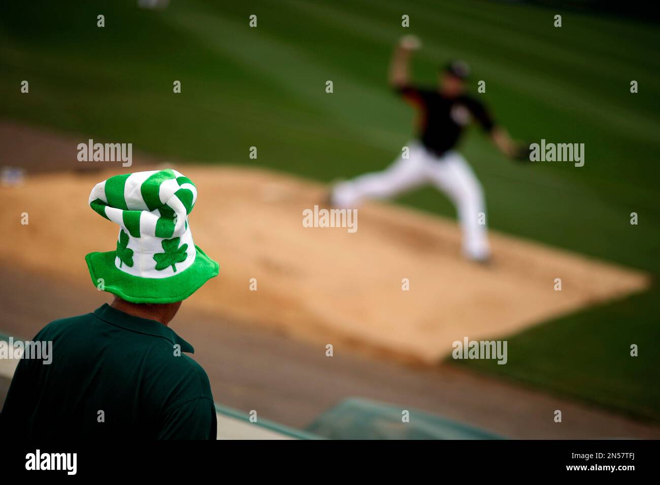 A spectator wearing a hat celebrating St. Patrick's Day watches as ...