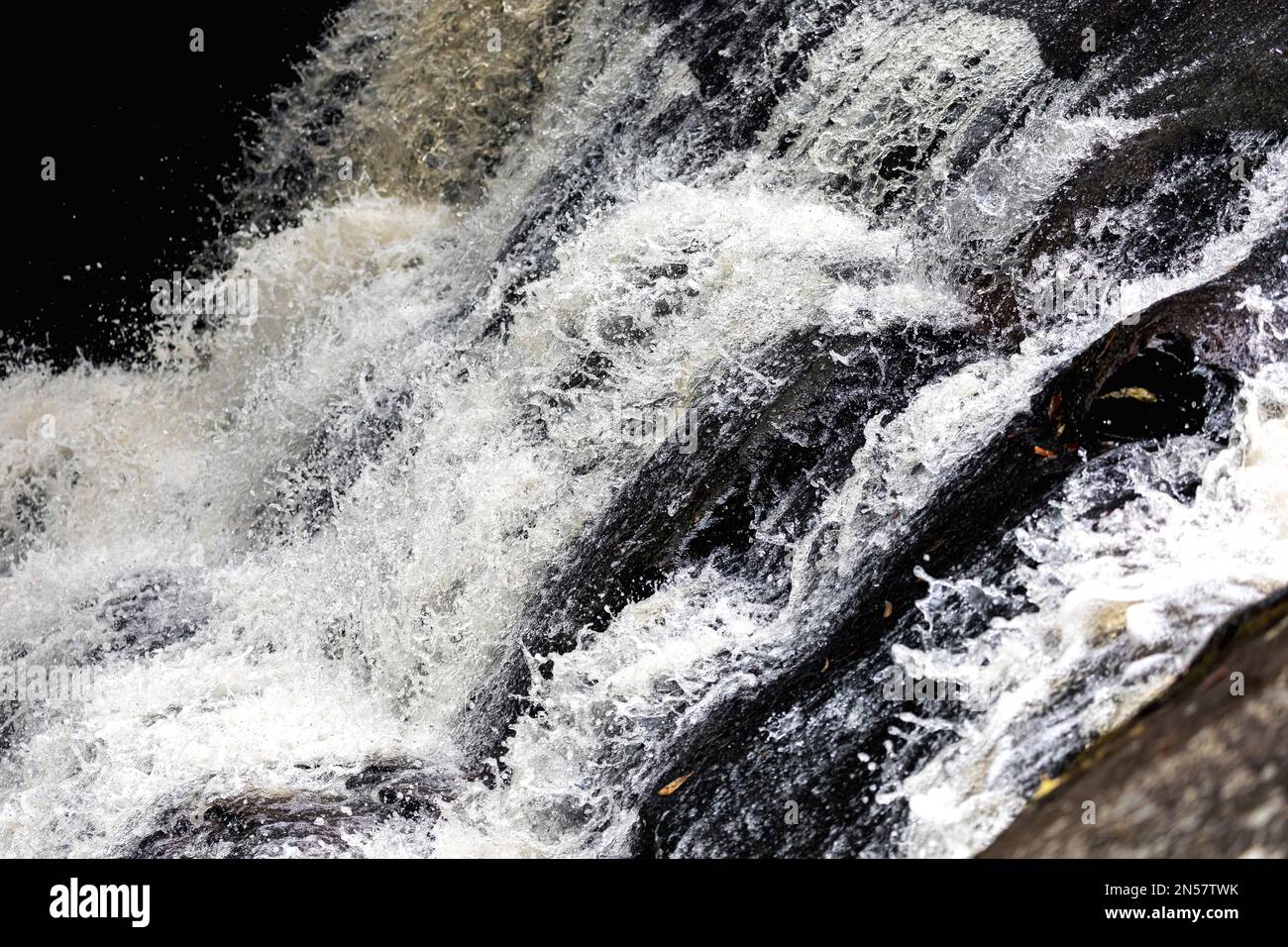 Splashing water on rocky slope of waterfall inside tropical rainforest ...