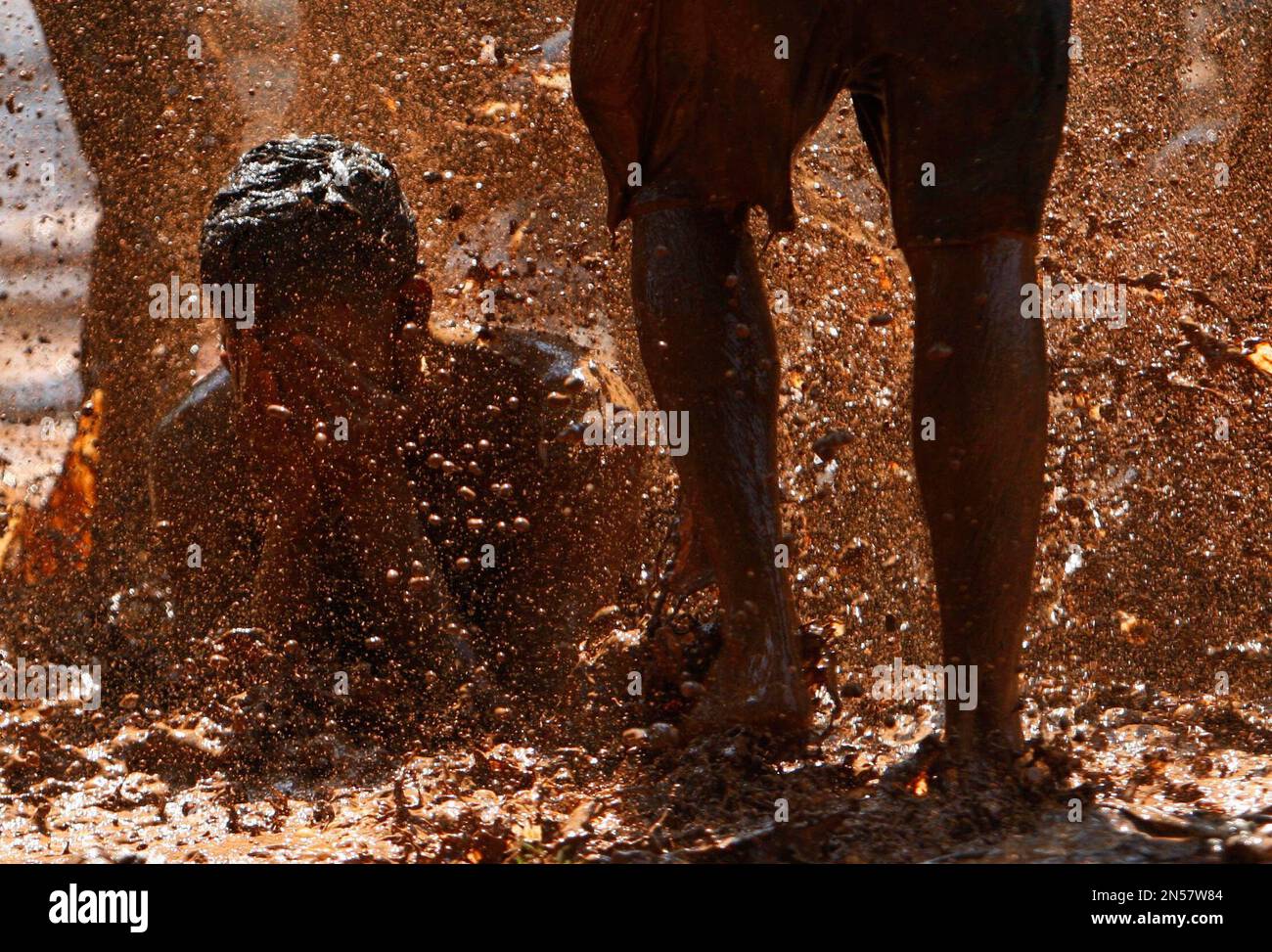 Indians play in a mud pool during celebrations marking Holi, the Hindu ...