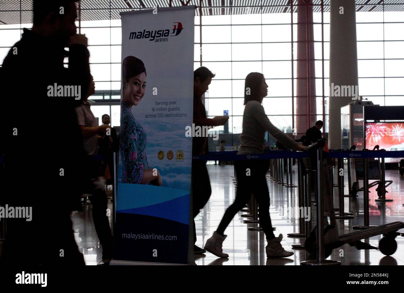 People walk past a Malaysia Airlines advertisement banner displayed ...