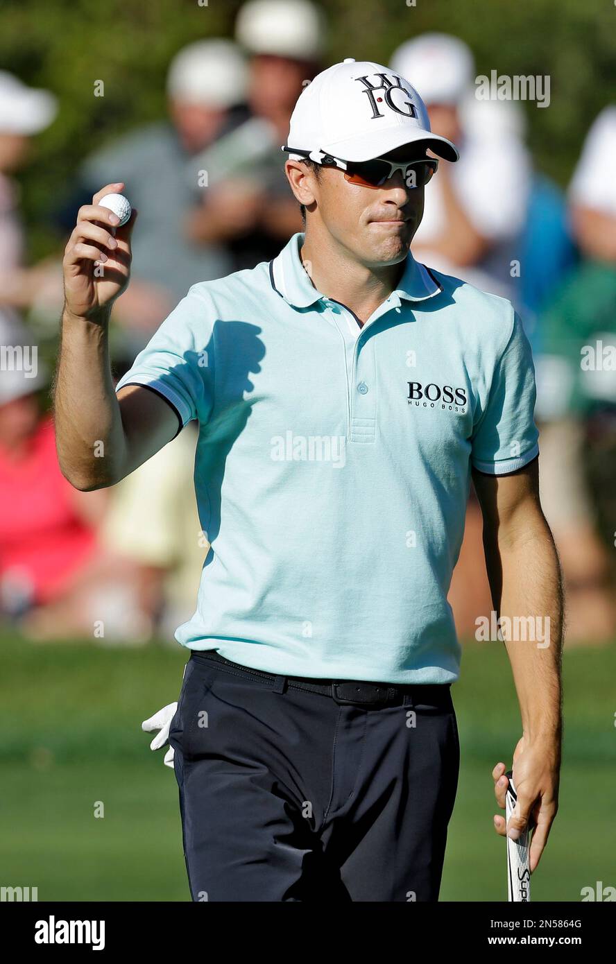 Scott Langley holds up his ball after making a putt on the 16th hole ...