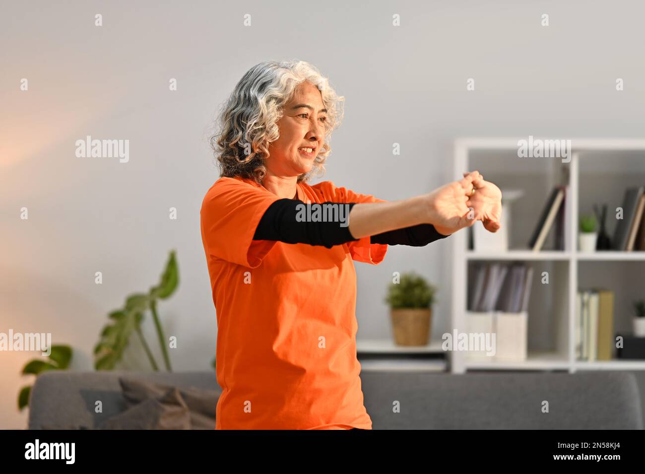 Active middle lady doing stretching exercises during home workout ...