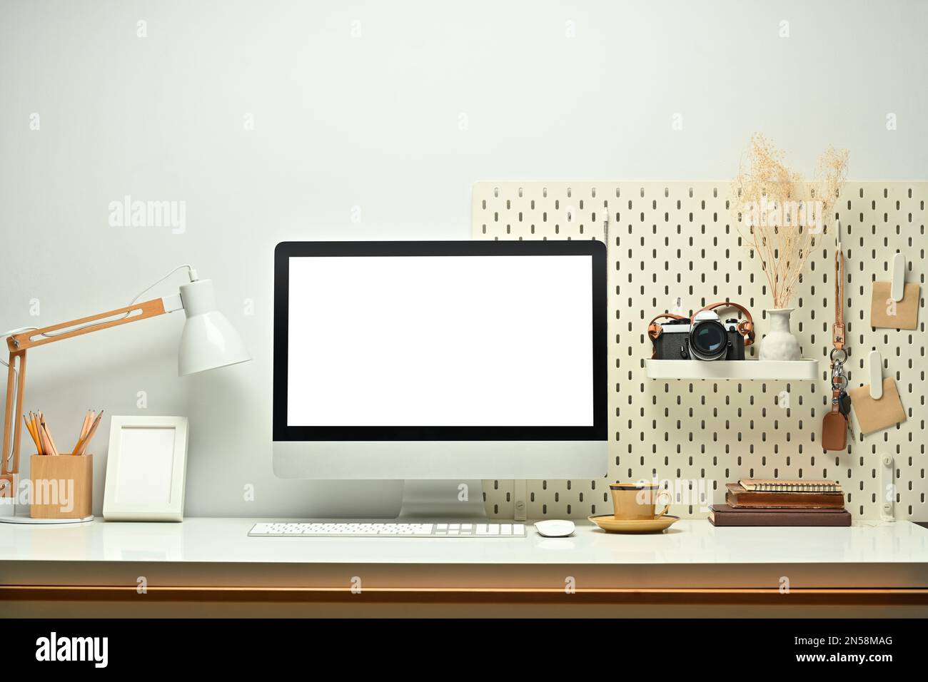 White blank screen computer monitor, picture frame, camera and books on ...