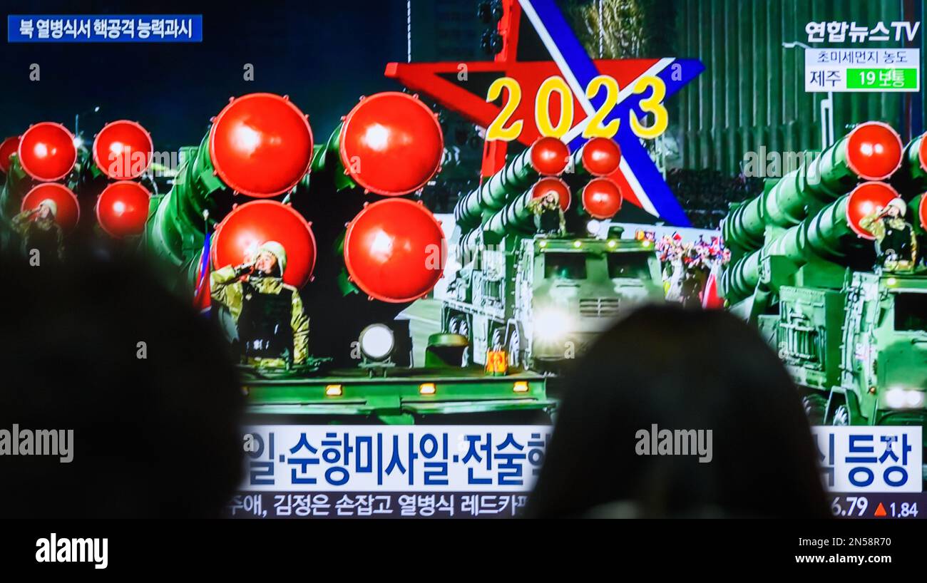 People watch a television screen showing a news broadcast with an image ...