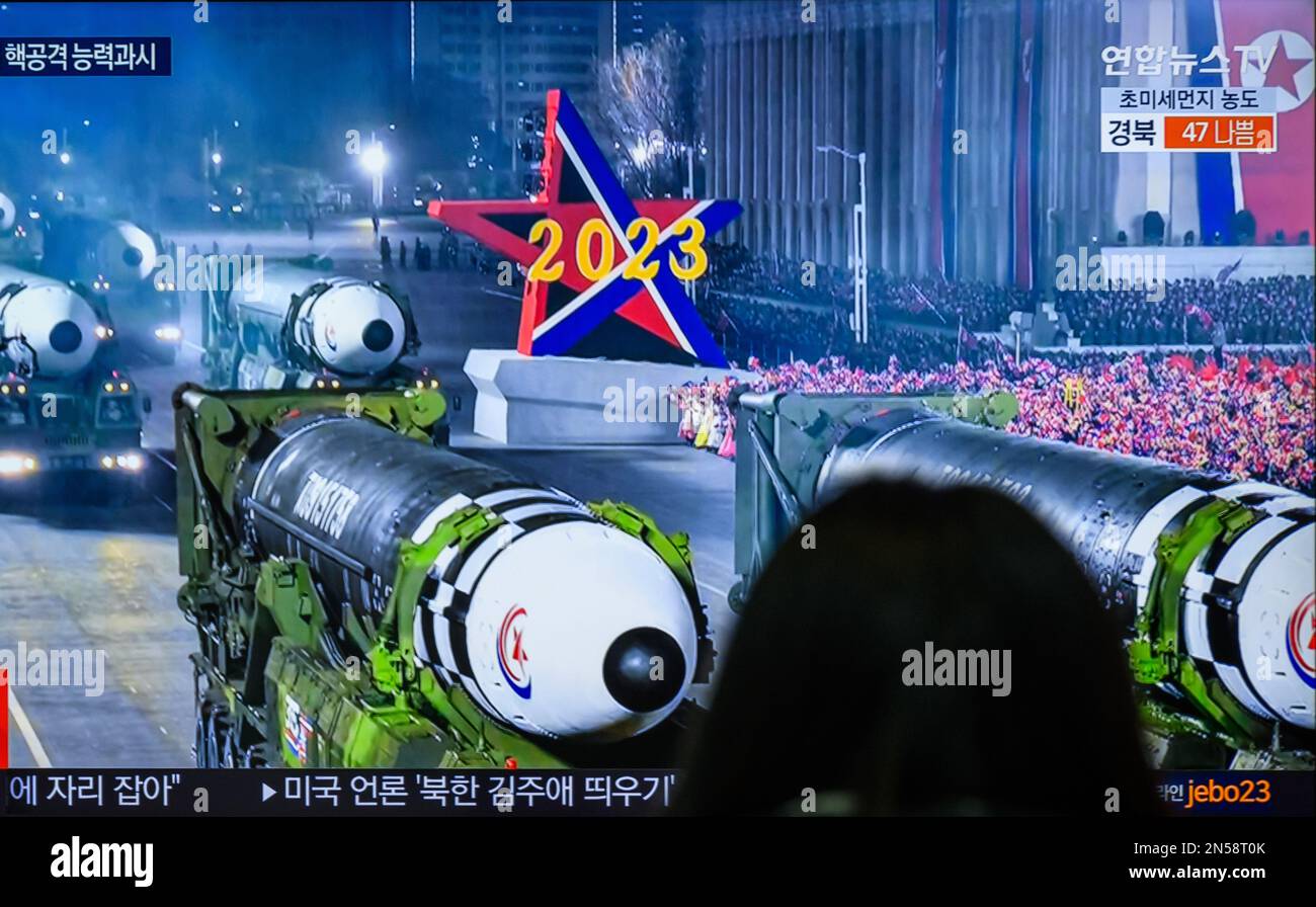 People watch a television screen showing a news broadcast with an image ...