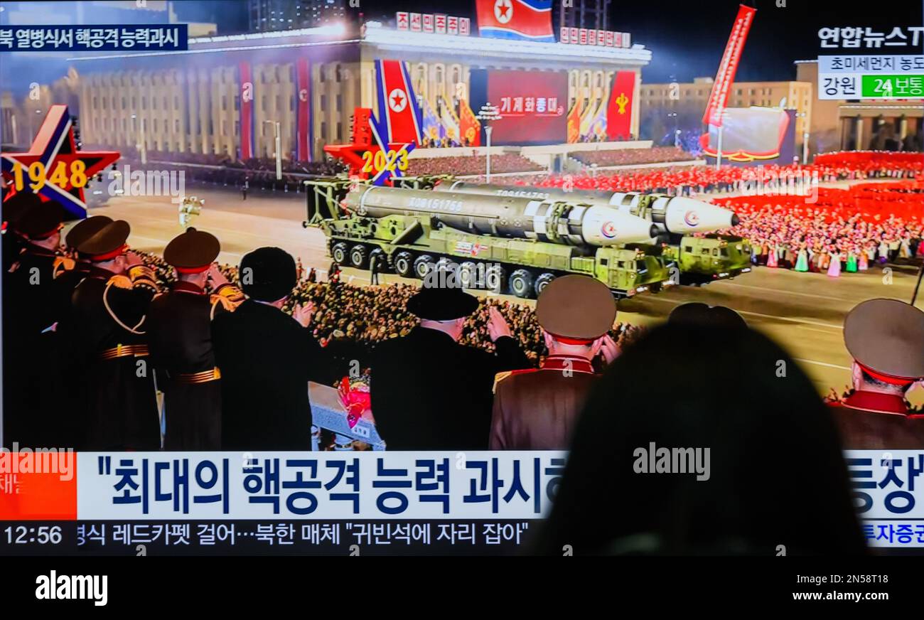 People Watch A Television Screen Showing A News Broadcast With An Image