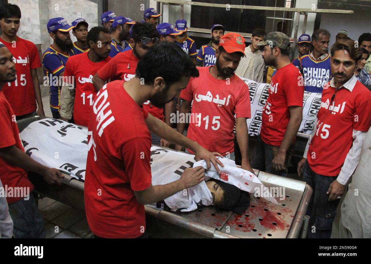 Pakistani volunteers look at a body of a woman killed in Karachi ...