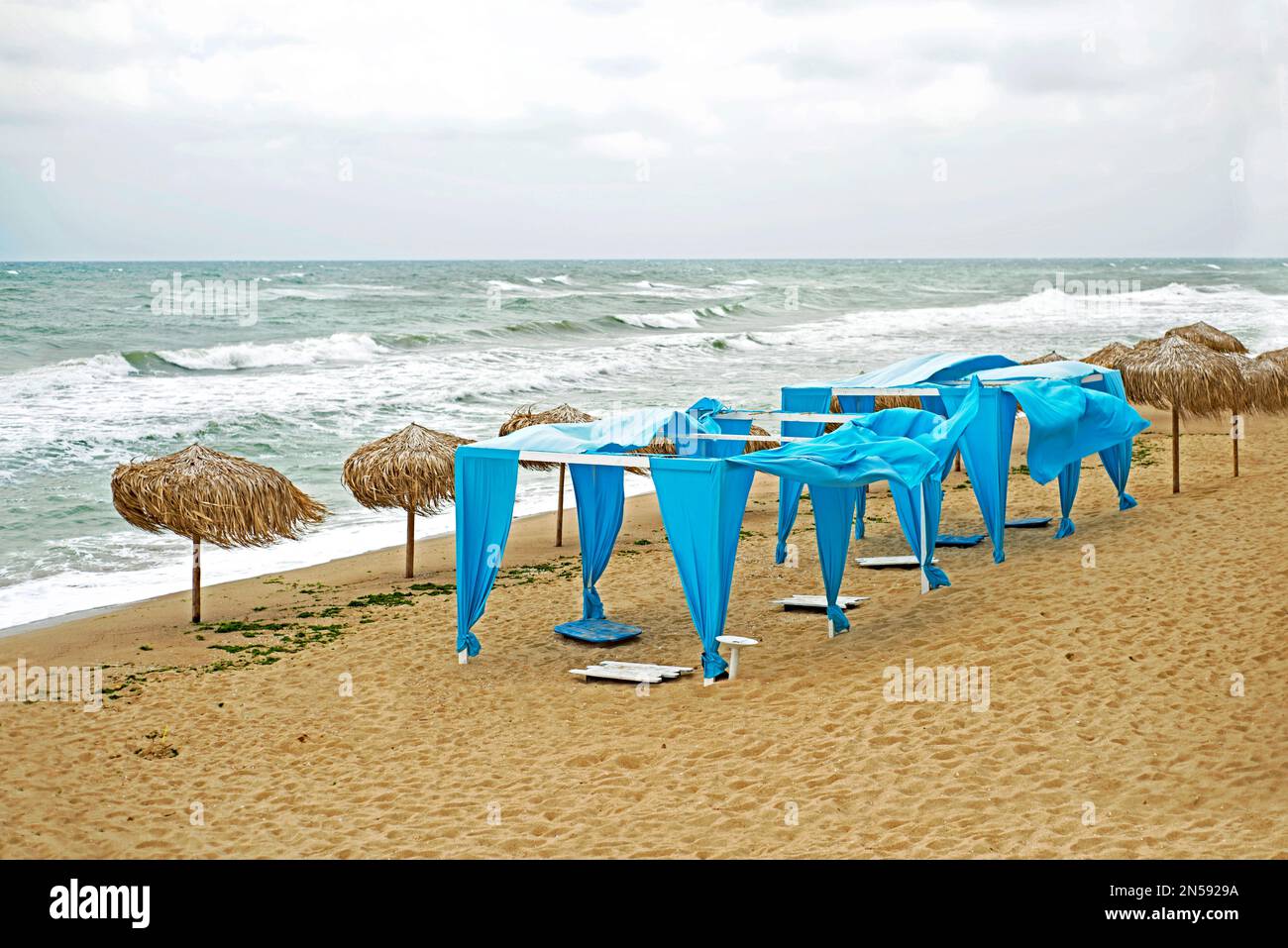Bad weather. Deserted beach. Empty sun loungers next to the stormy sea ...