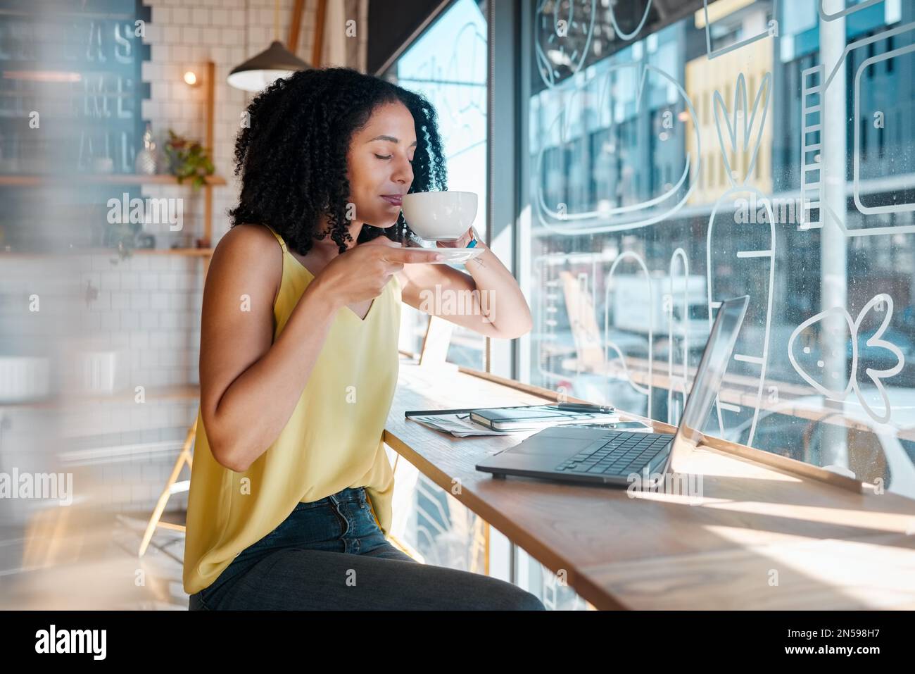 Window, laptop and internet cafe with a black woman blogger smelling a ...