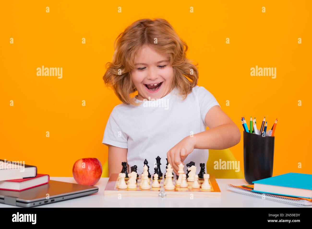 Child with chess on yellow isolated studio background. Kid playing chess. Clever child thinking ...