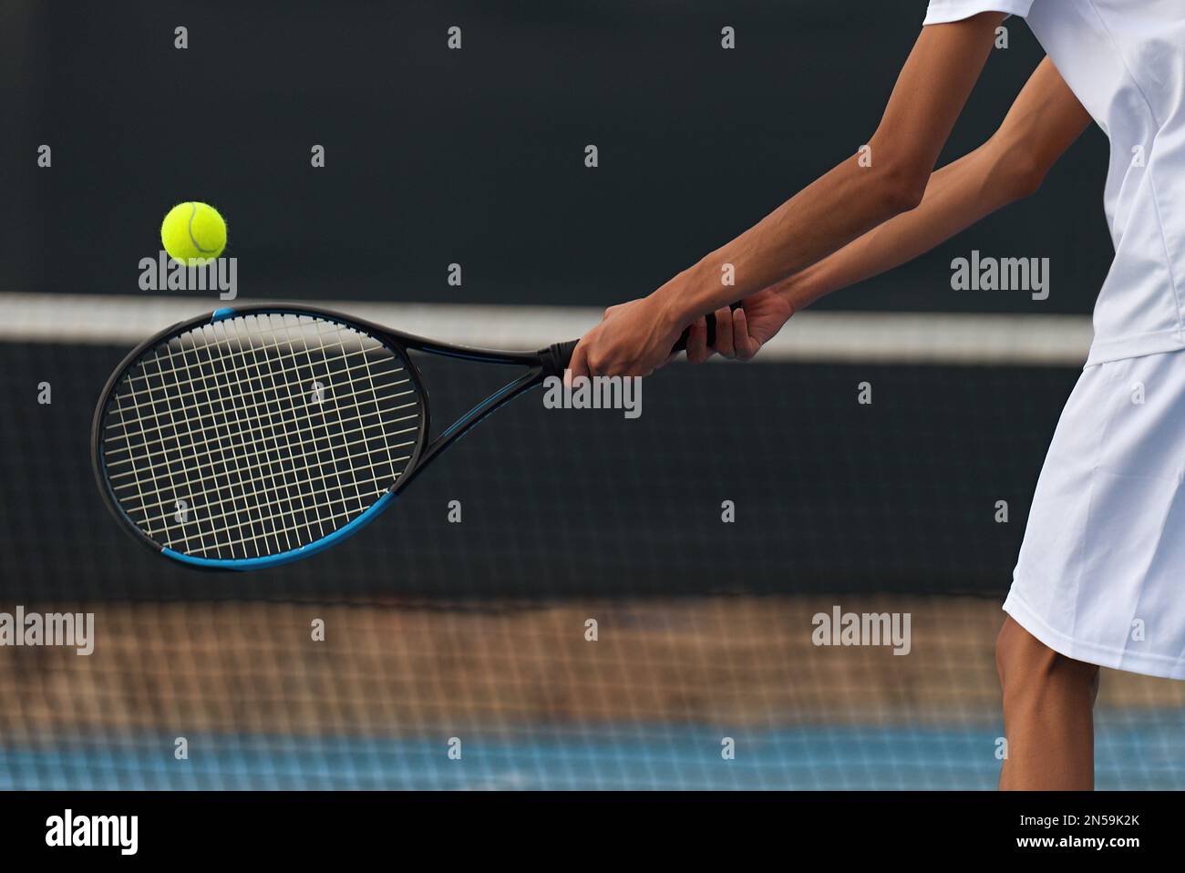 Male tennis player hitting backhand by net on the tennis court Stock ...