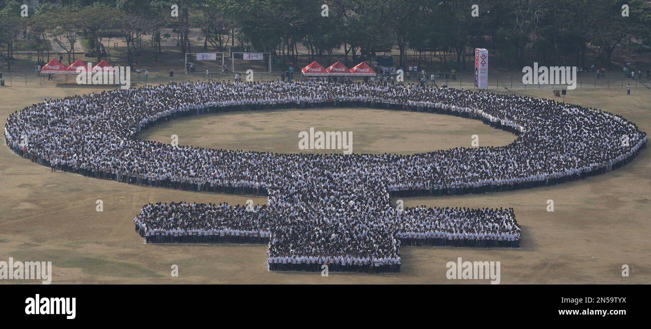 A crowd gathers to form a woman symbol as they celebrate International ...