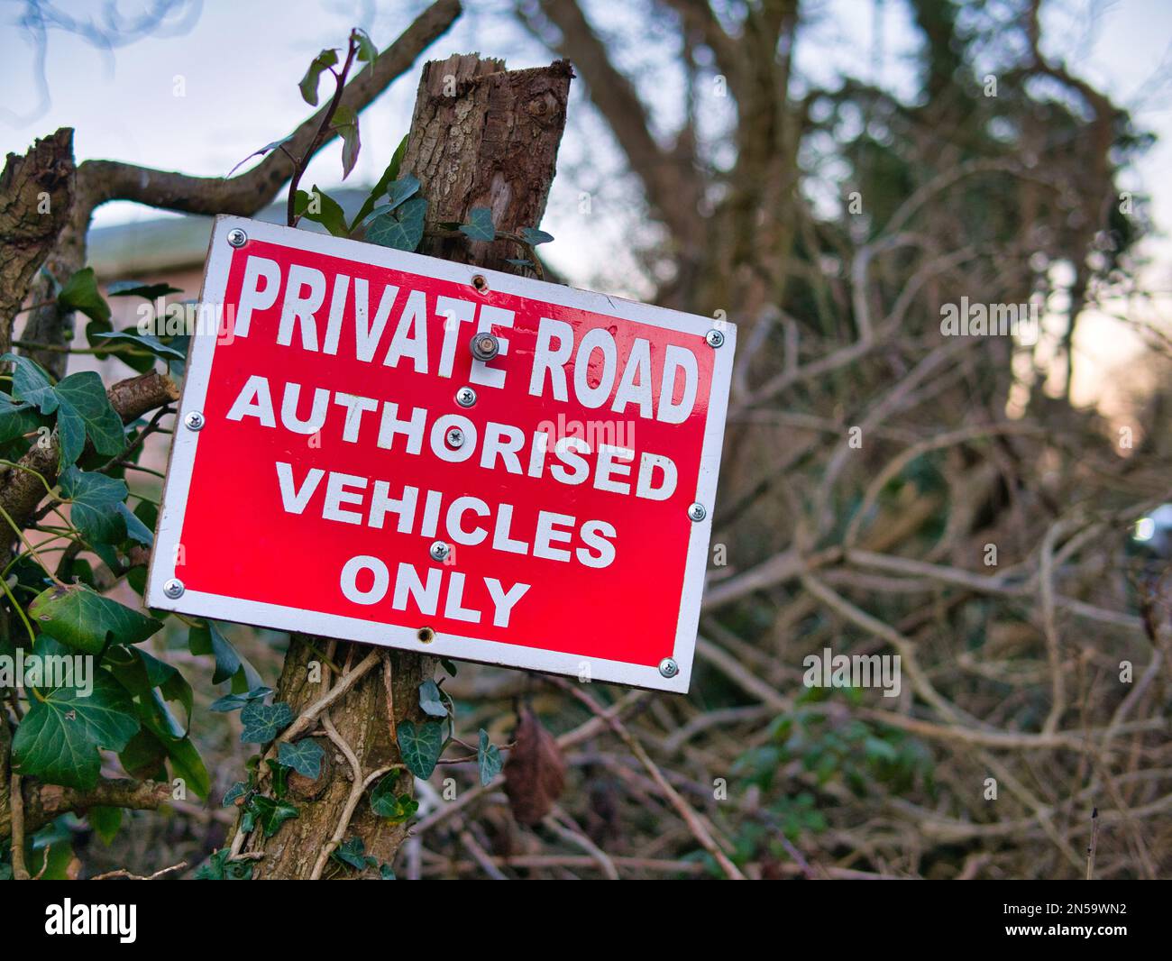 A prominent sign of white words on a red background in a hedgerow ...