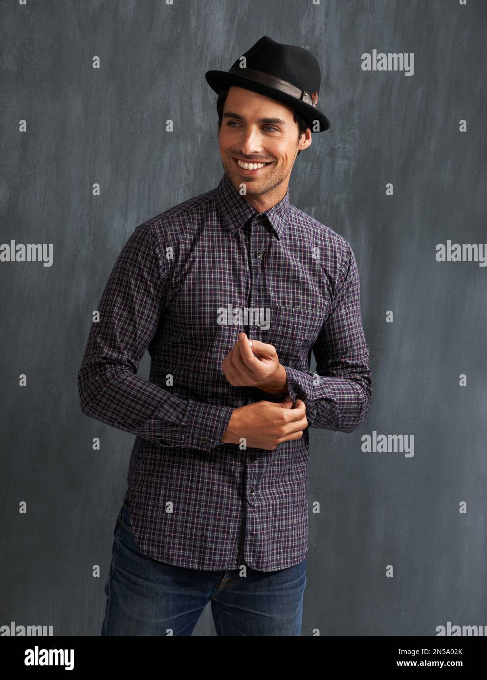 His clothes always fit just right. A hip young man buttoning his shirt ...