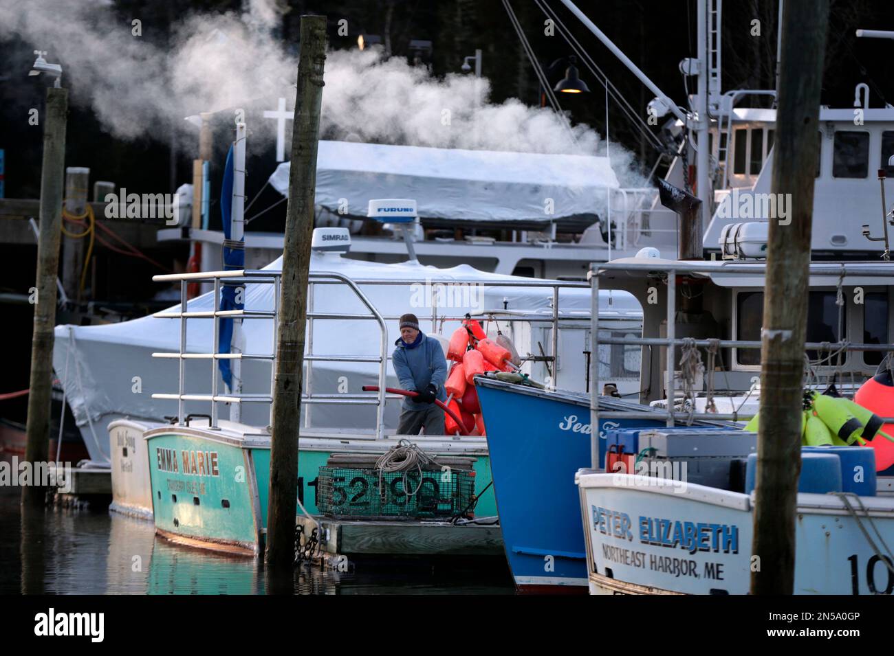 Lobsterman Mark Fernald whacks a frozen hose to break up the ice before ...