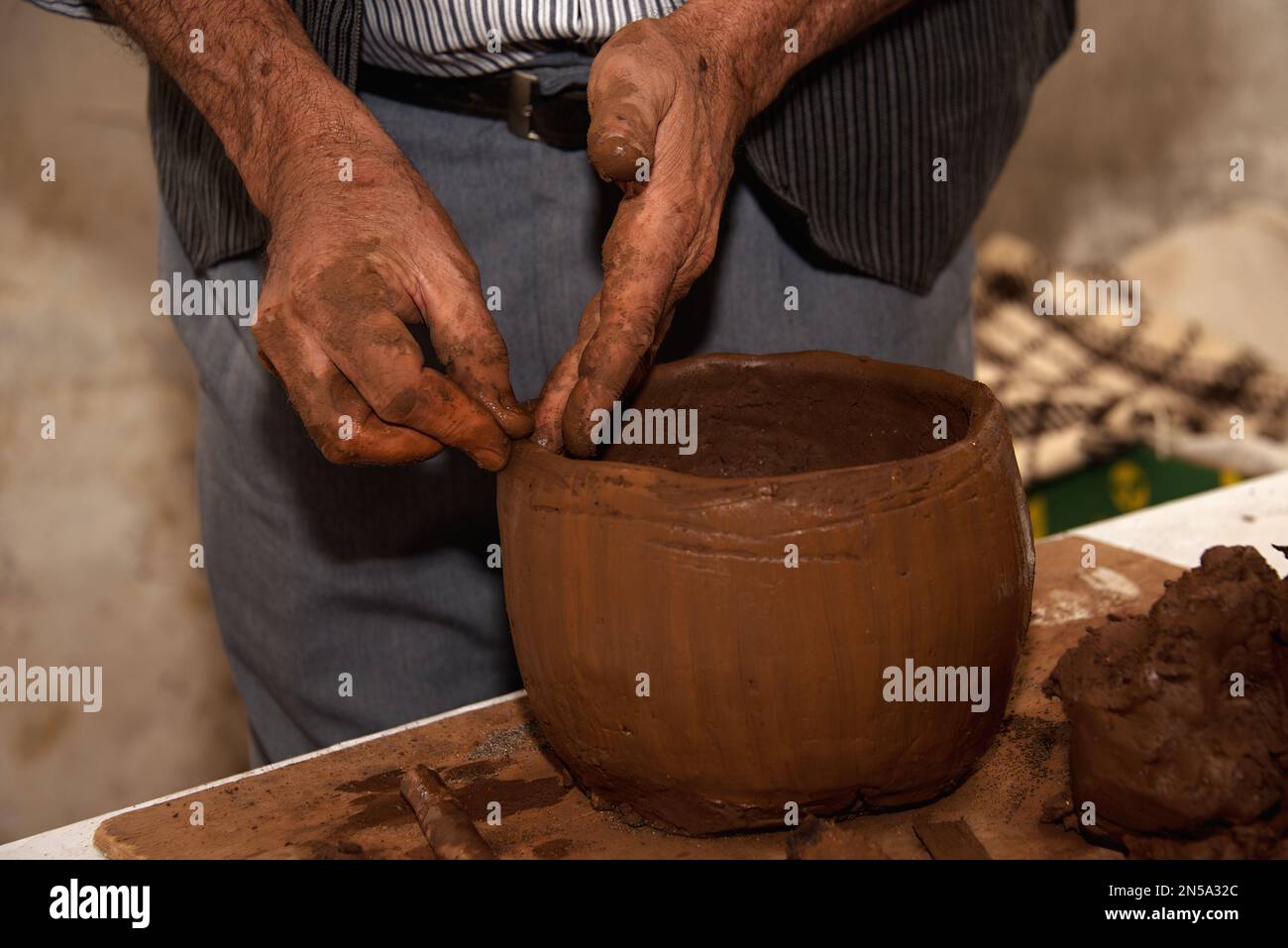 Artisan hands shaping moulding clay pot with raw clay material. Closeup ...