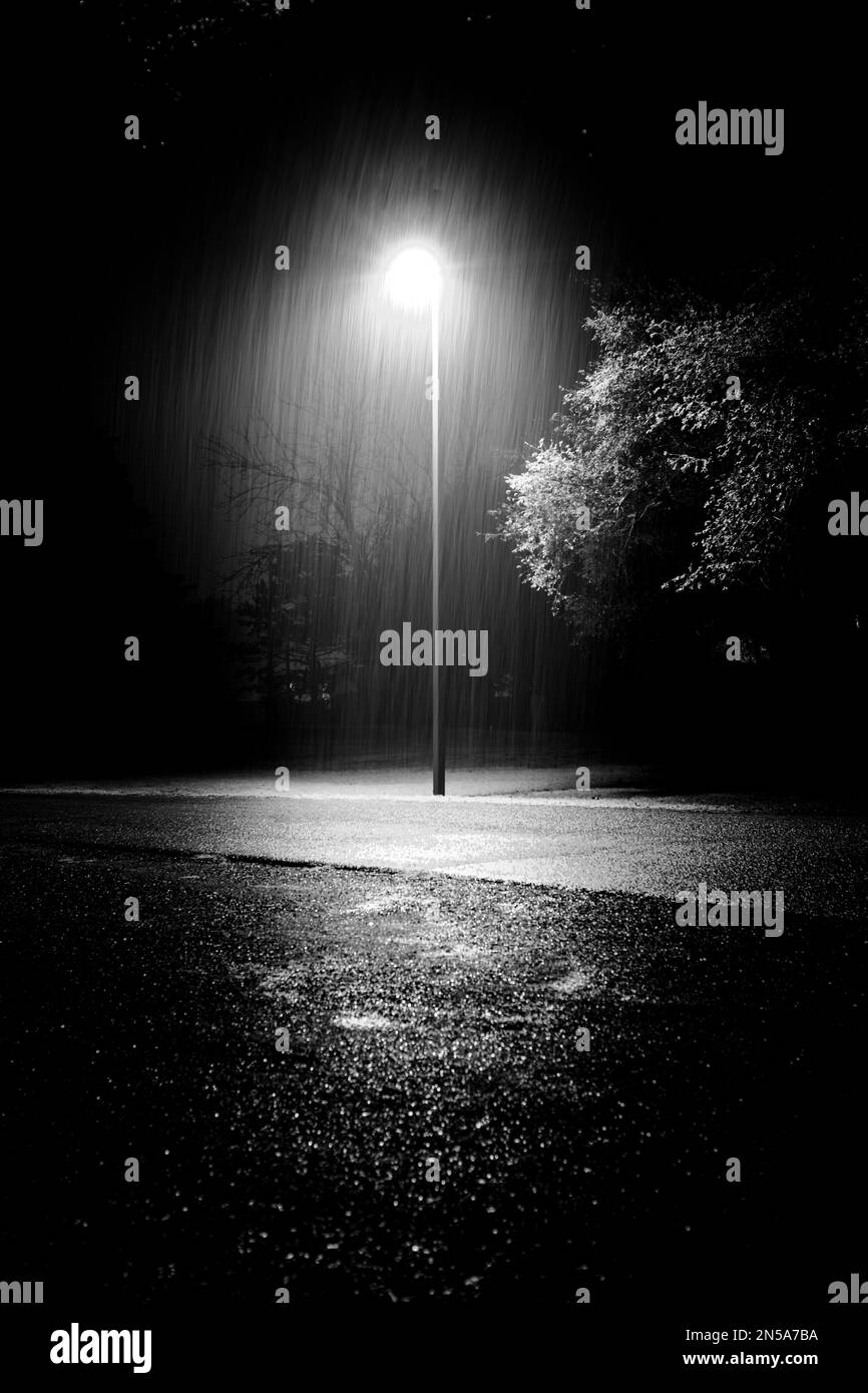 A vertical shot of heavy rain illuminated by street light pouring in ...