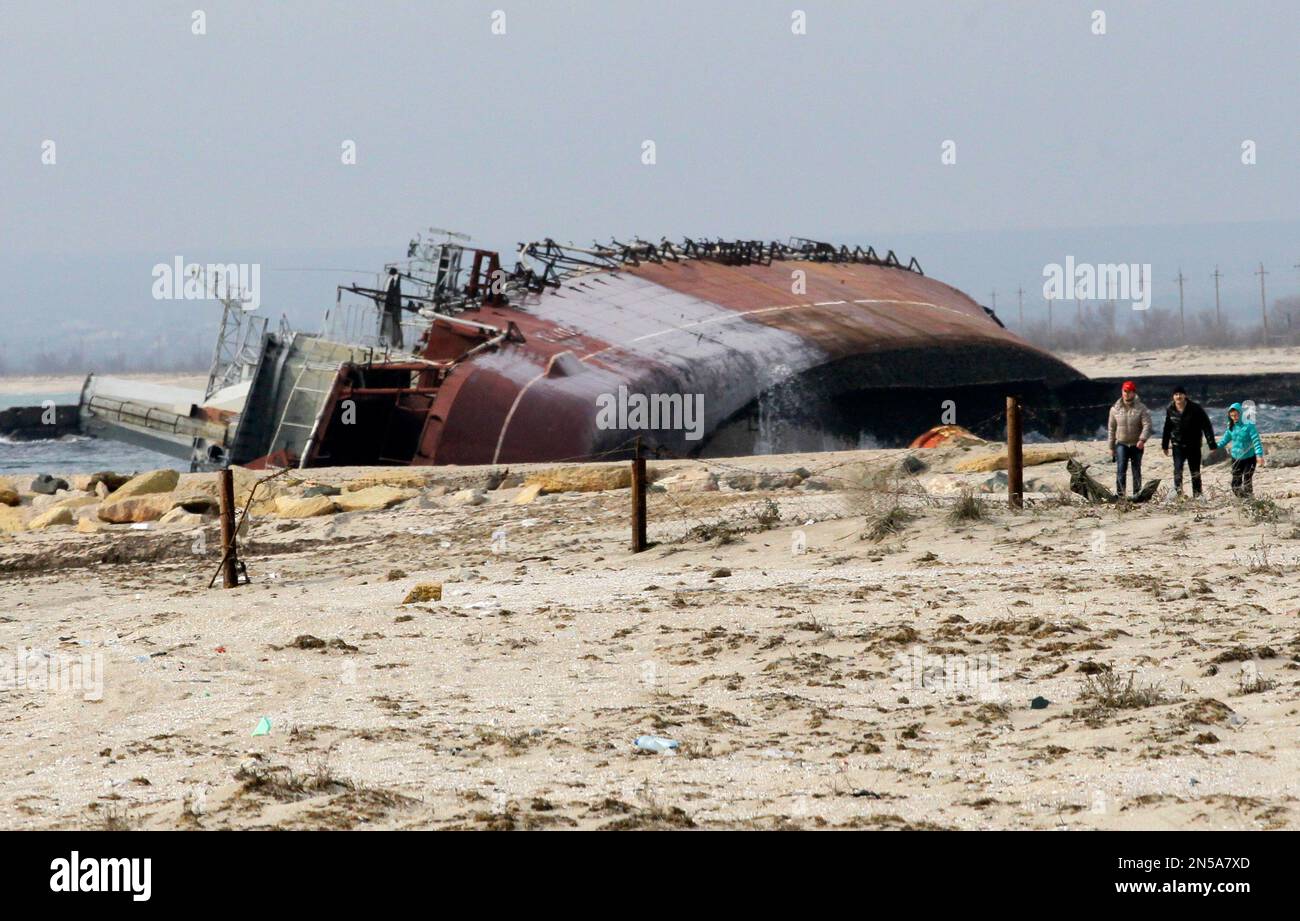 People walk past the scuttled decommissioned Russian vessel "Ochakov ...