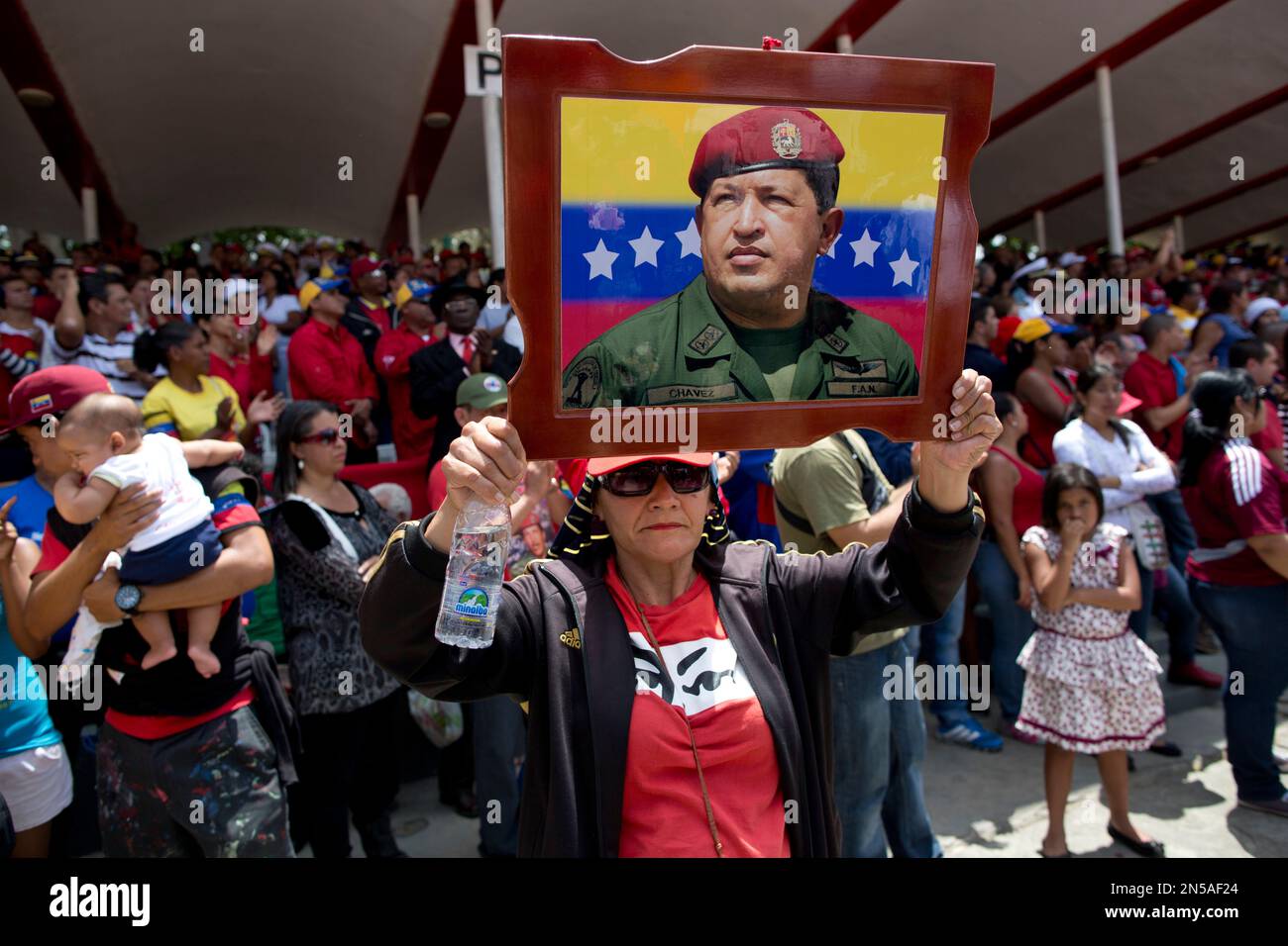 A woman holds up a portrait of Venezuela's former President Hugo Chavez ...