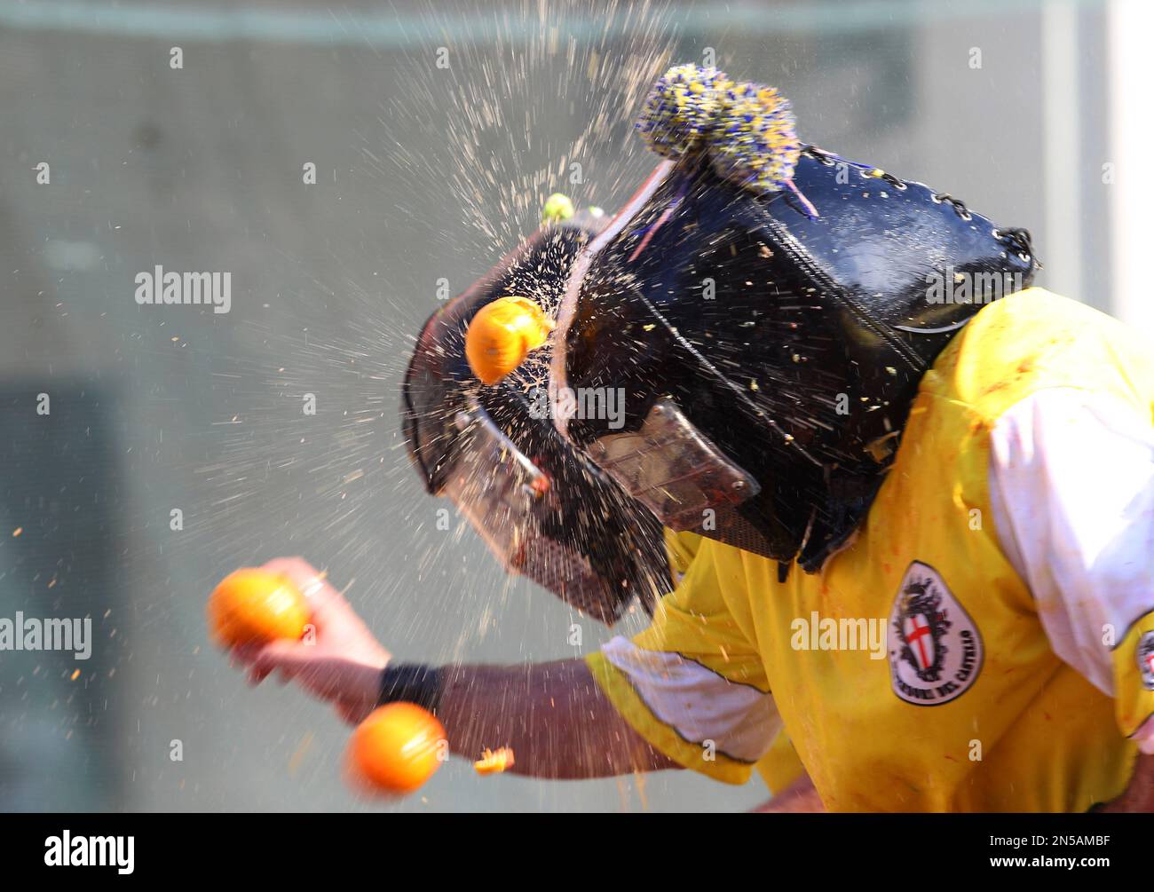 People wearing protection helmets and costumes throw oranges as part of ...