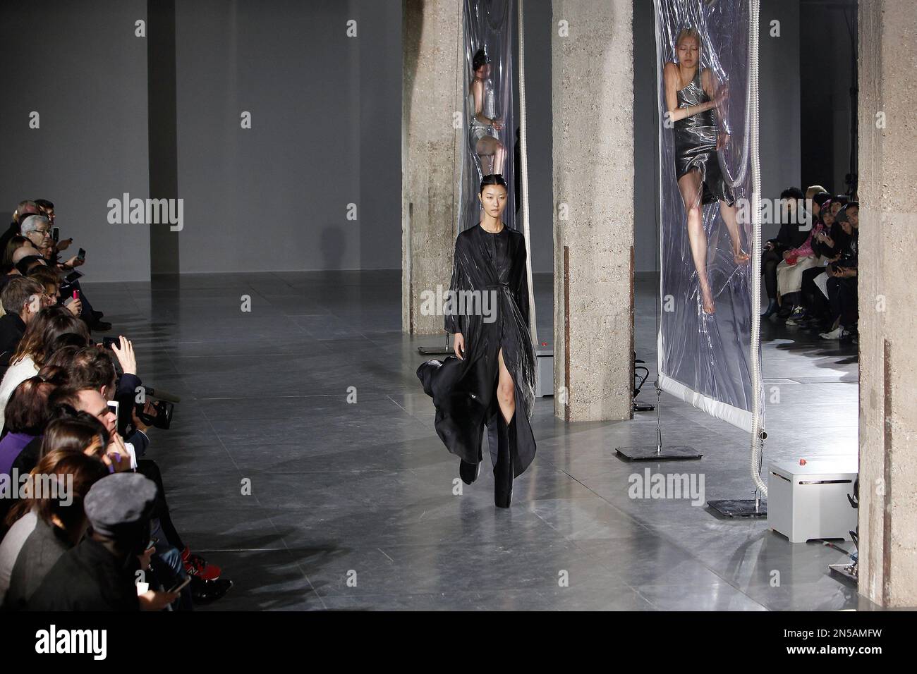 A model walks on the runway, centre, as two other models are suspended ...