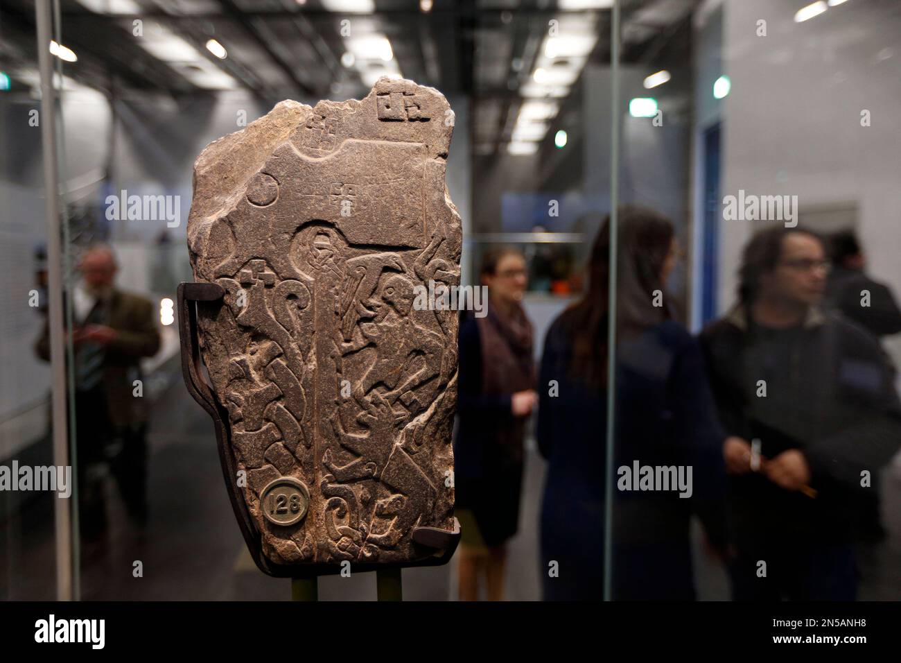 Visitors walk past a fragment of a Viking engraved stone as they view a ...