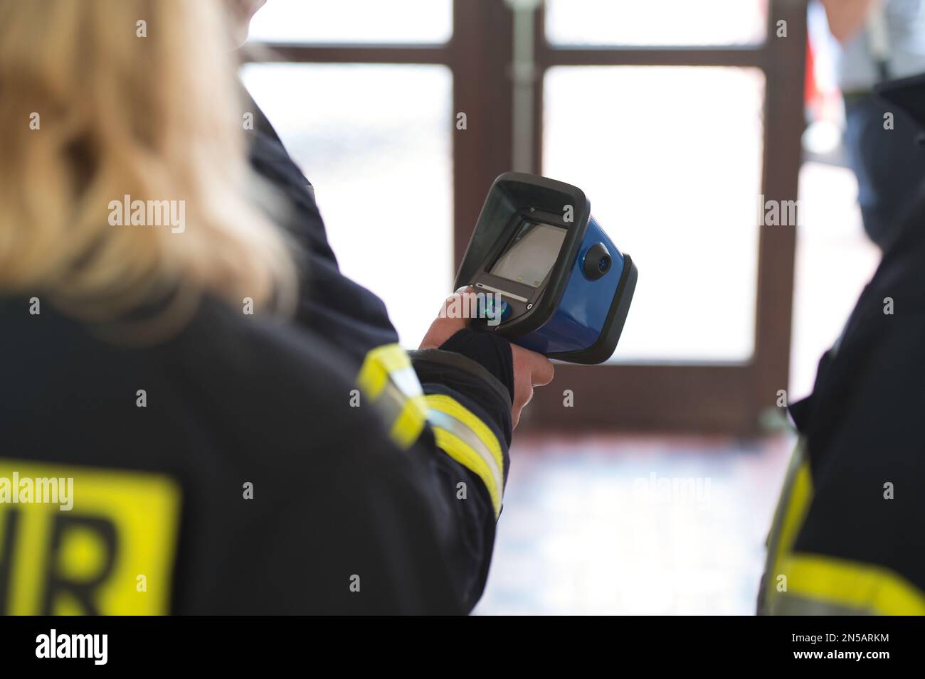 Firefighter looks at the screen of a thermal imaging camera in a ...