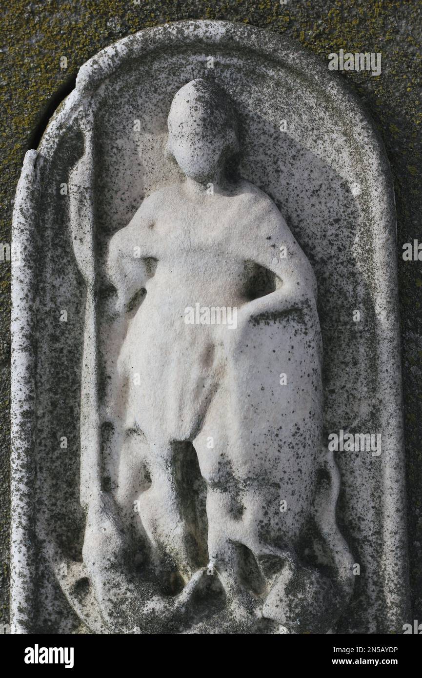 A worn and weathered natural stone statue of Saint Michael the ...