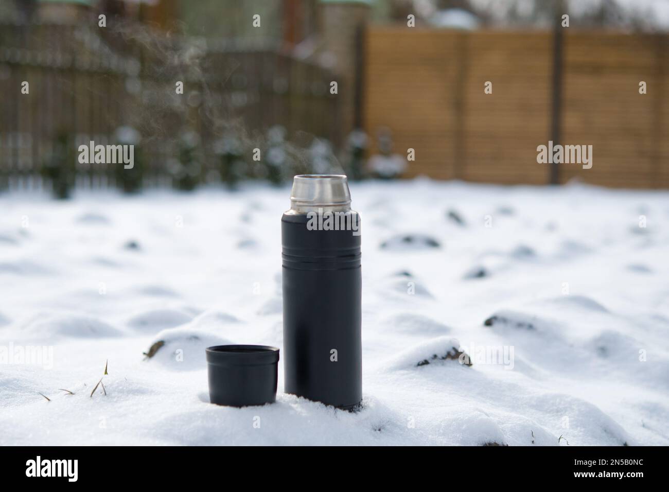 Steel thermos with hot tea, coffee on snowy. Winter landscape ...