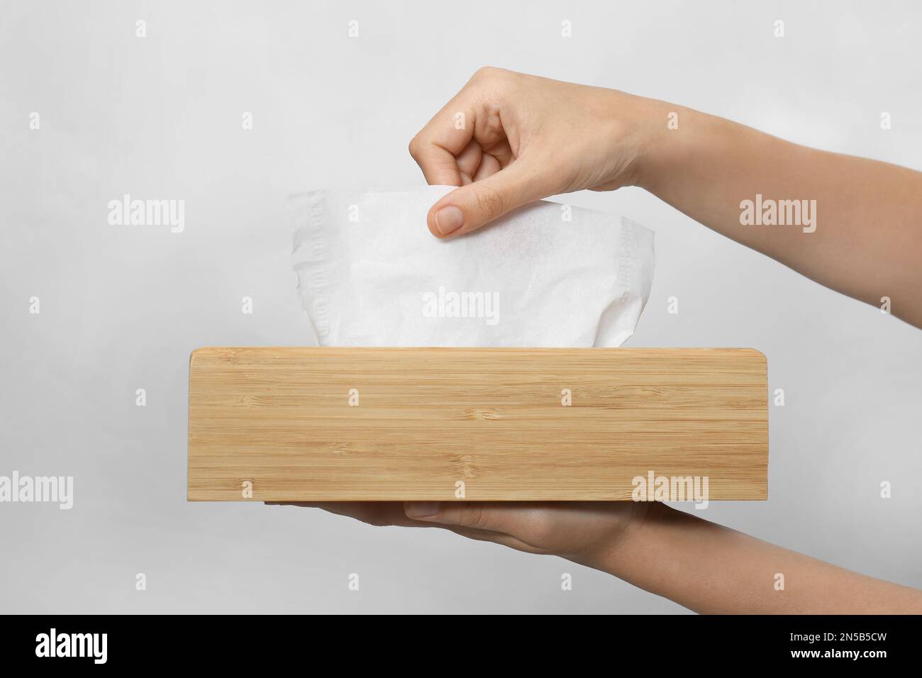 Woman taking paper tissue from holder on light background, closeup ...