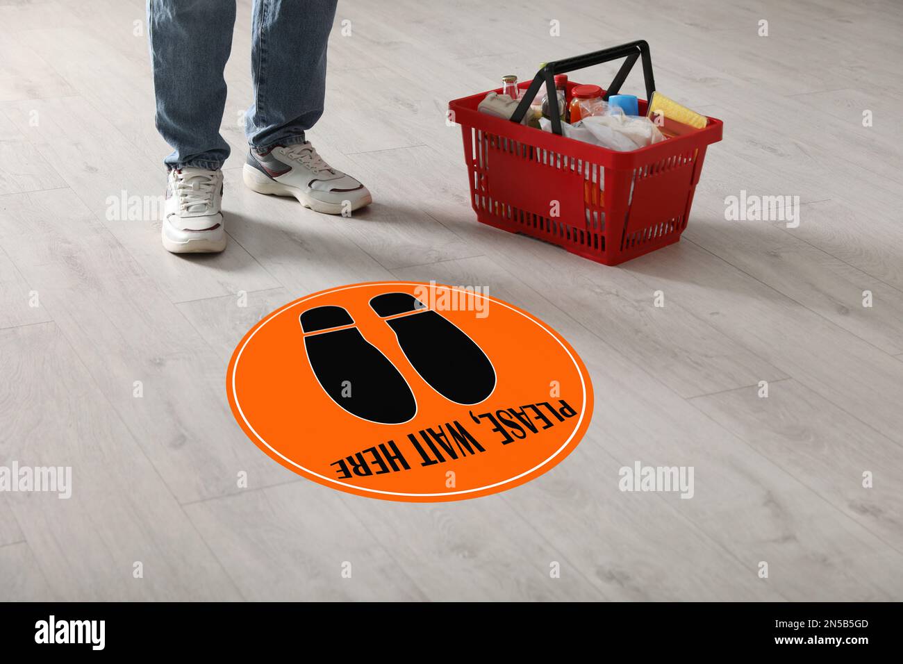 Man near sign PLEASE, WAIT HERE in supermarket. Coronavirus pandemic ...